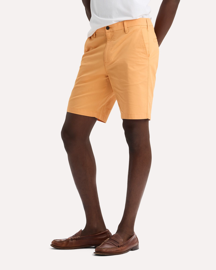 Side view of model wearing Apricot Tan Ultimate 9.5" Shorts, Straight Fit.